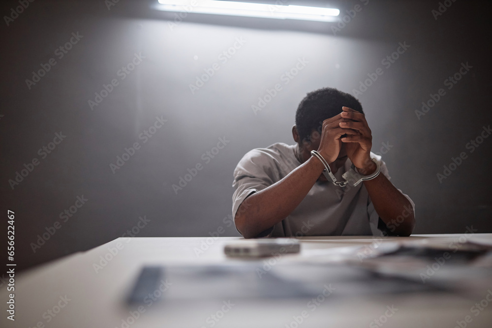 Minimal portrait of Black young man wearing handcuffs crying in remorse ...