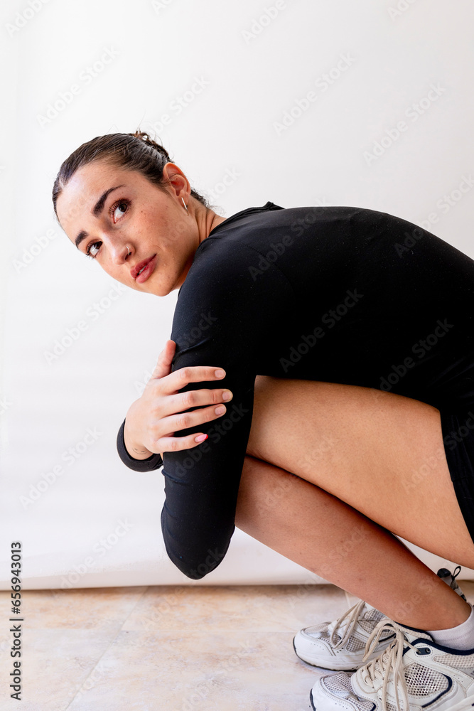 Beautiful woman crouching in front of backdrop Stock Photo | Adobe Stock