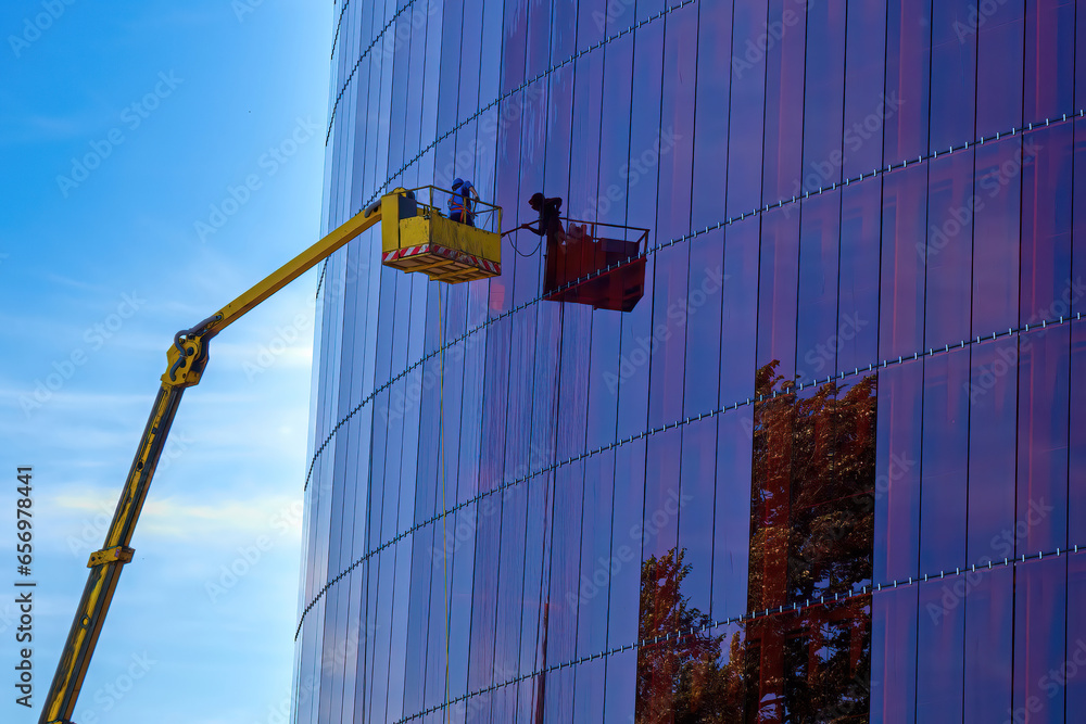 Window cleaning work at height on a lifting platform. Washing office ...