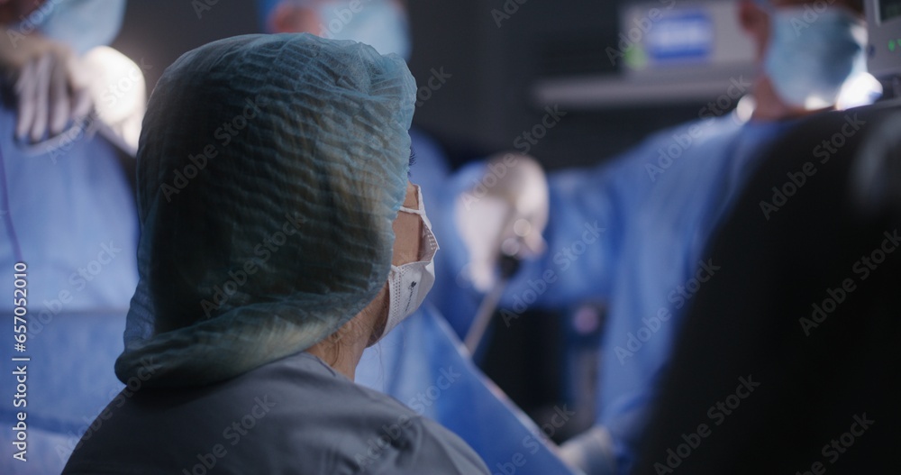 Female medic sits in modern operating room and checks condition of ...