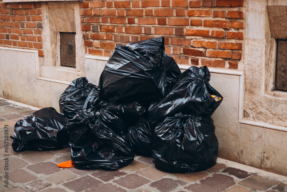 Pile of black garbage on the footpath at side road in big city ...