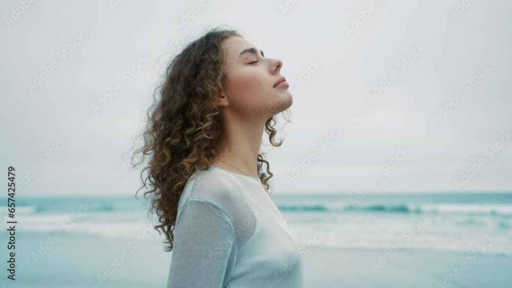 Calm young woman taking deep breath of fresh air meditating with eyes ...