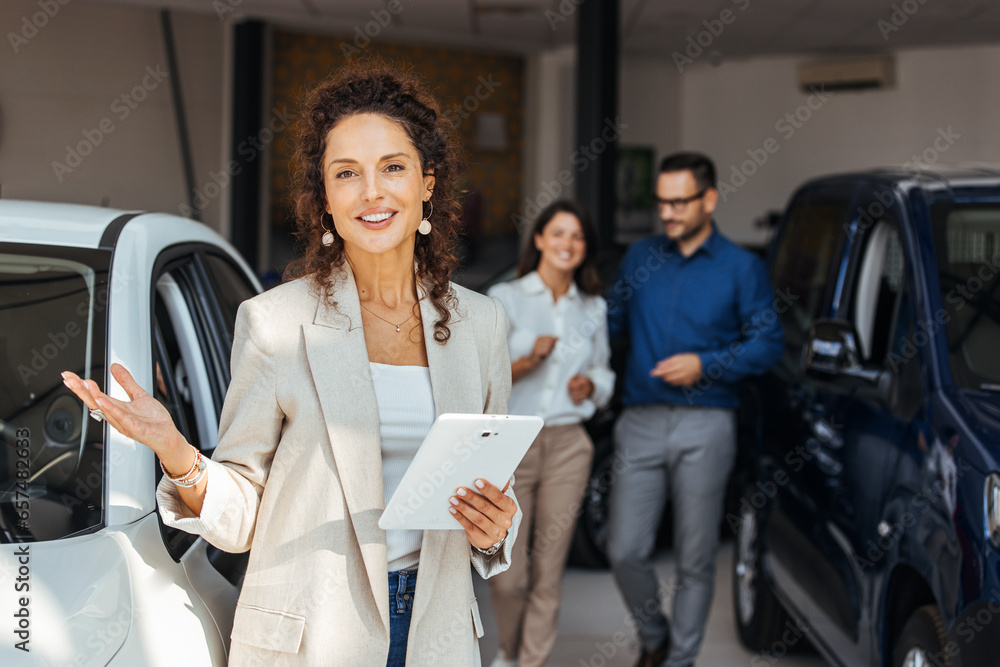 Happy female salesperson working on touchpad in a car showroom ...