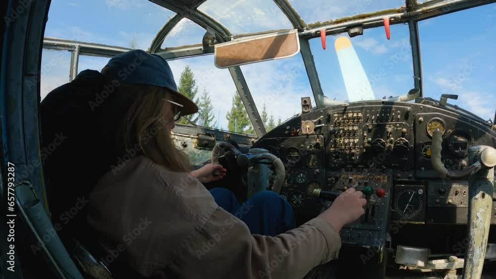 A girl sits at the steering wheel in the cockpit of an An-2 airplane ...