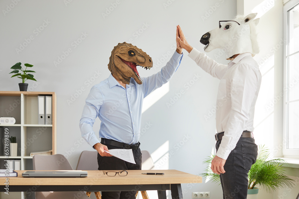 Two businessmen in animal masks giving high five celebrating ...