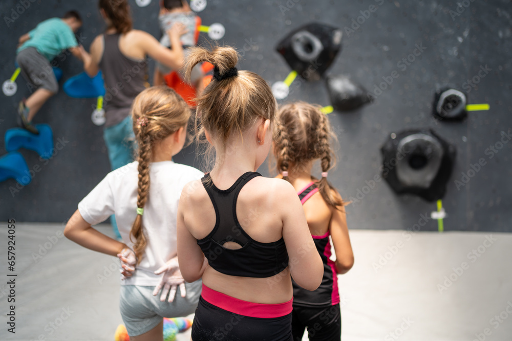 Three girls in sport clothes on climbing session. Back view of kids ...