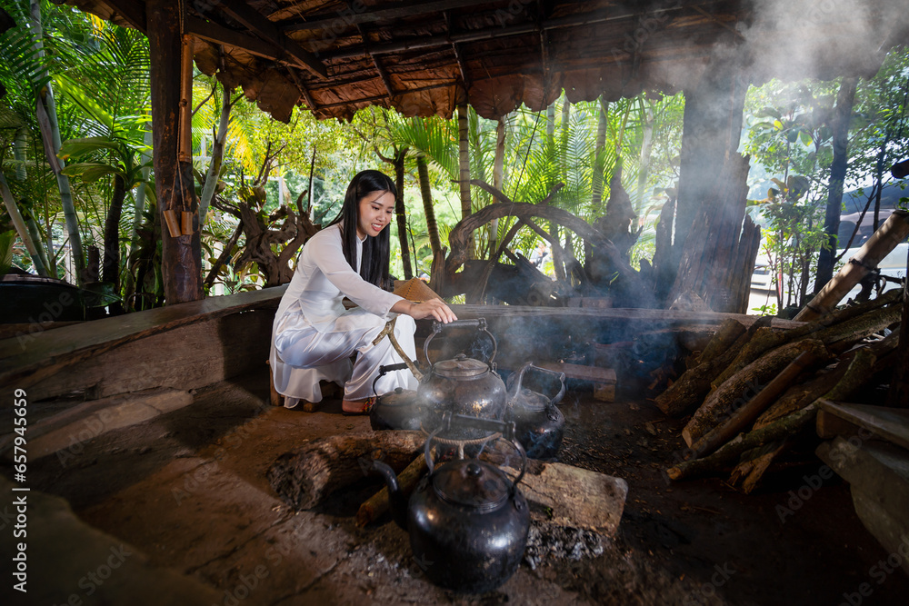 Beautiful Asian woman wearing white Ao Dai dress and boiling water in ...