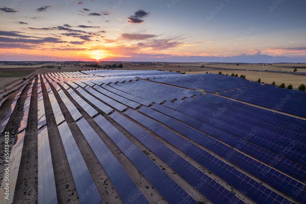 Aerial Top View of a solar power plant with sunset reflection on the ...