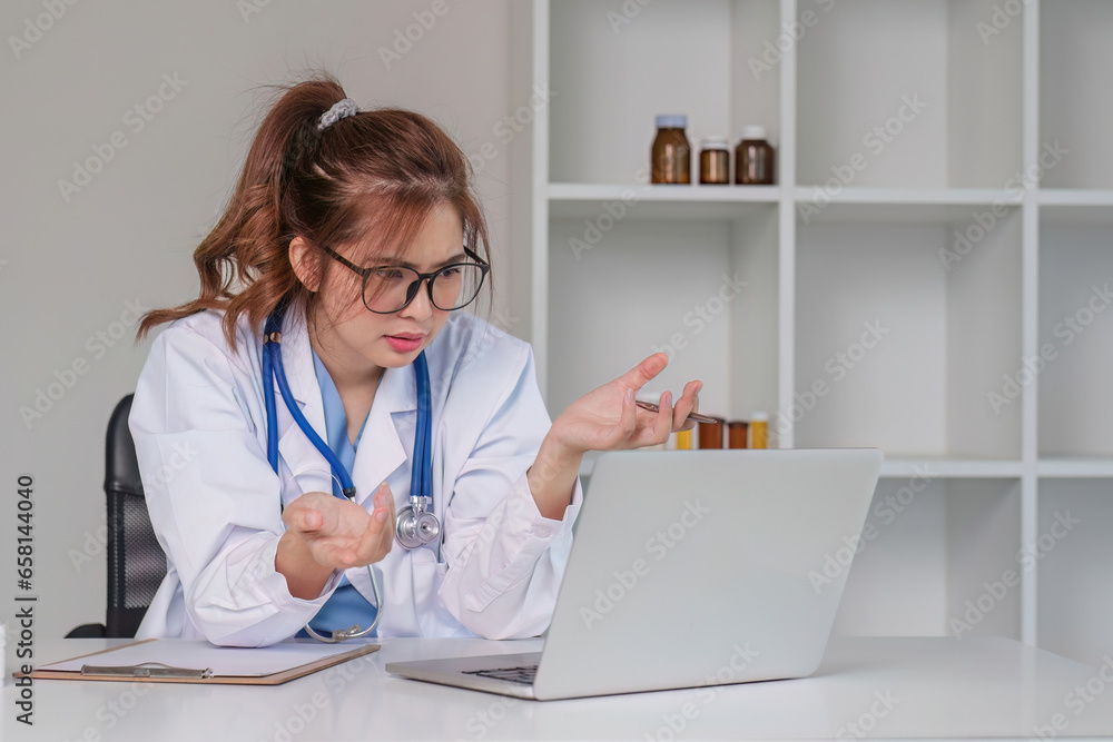 Stressed young female doctor looking at laptop, work related chaos ...