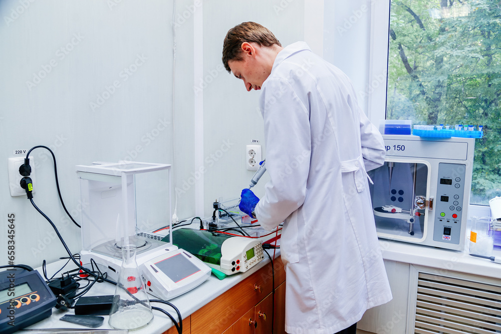 Scientist with gloved hand putting DNA sample into real-time PCR-cycler ...
