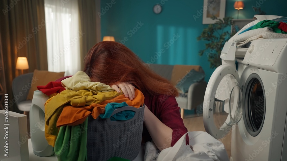 Redhead woman sitting next to a washing machine, laying her head on a ...