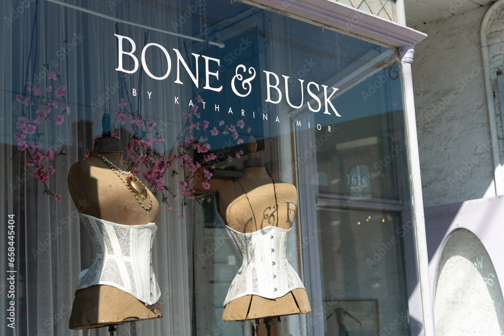 exterior window with sign of Bone & Busk with mannequin busts wearing ...
