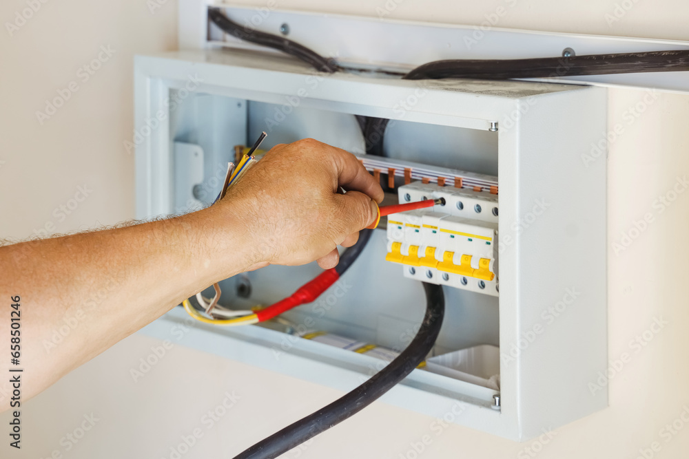 An electrician's hand with a multimeter probe on an electrical ...