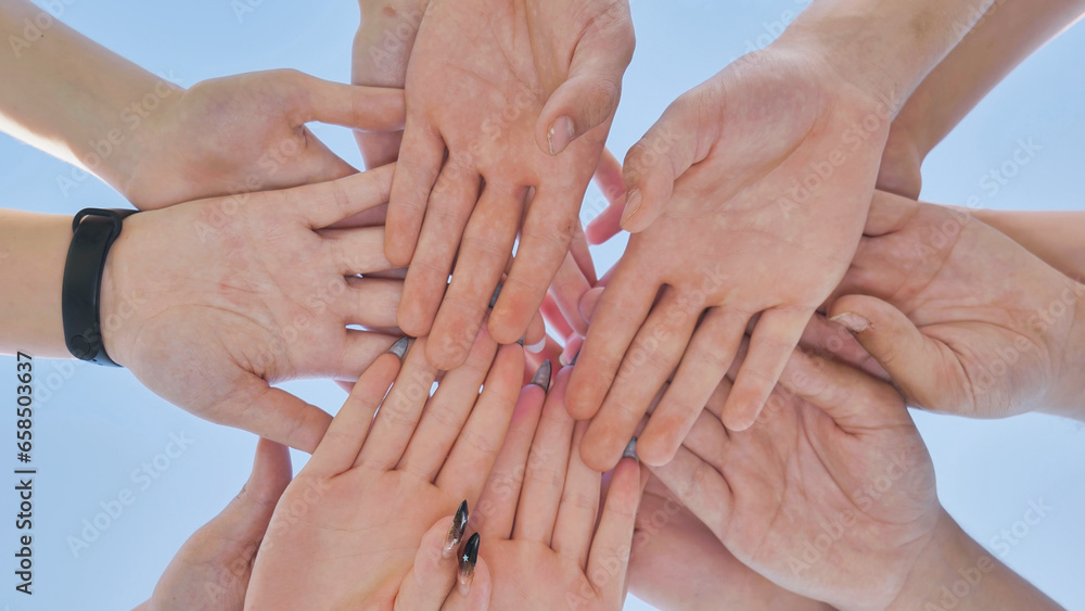 Friends putting their hands together in a sign of unity and teamwork ...