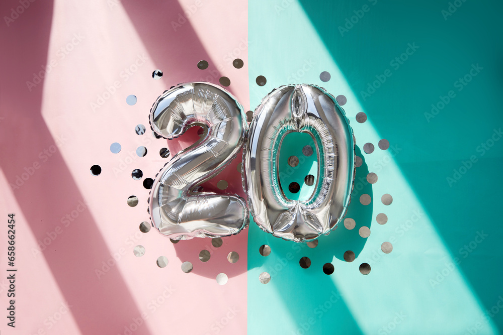 Silver numbers 20 twenty years balloons among confetti in sunlight on ...