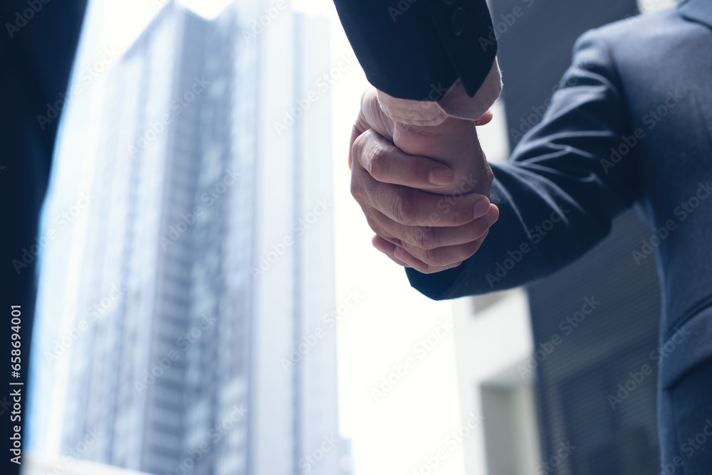 Businessmen making handshake with buildings in the city as background ...