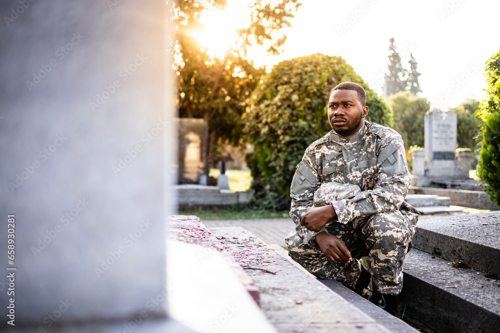 Sad moment of soldier in uniform kneeling by the grave of his fallen ...