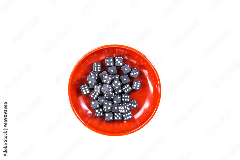 Tiny black and white dice pile in a red bowl isolated over white top ...