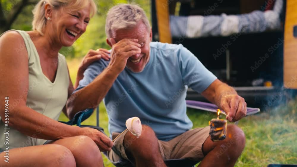 Senior retired couple camping in countryside in RV toasting ...