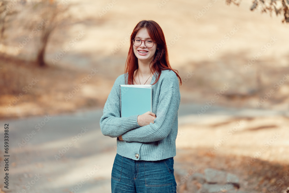 Smiling girl student in glasses stands holding notebooks. School and ...