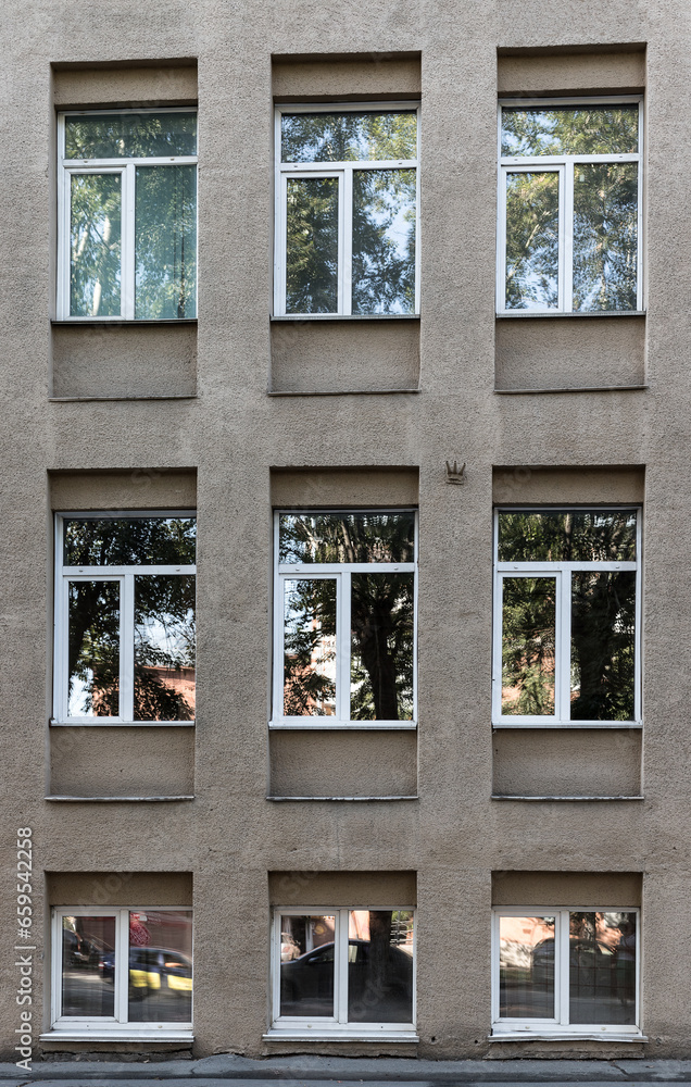 There are many windows in a row on the facade of a city building. a ...