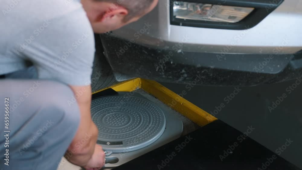 A car service employee installs a wheel adapter with a target on the ...