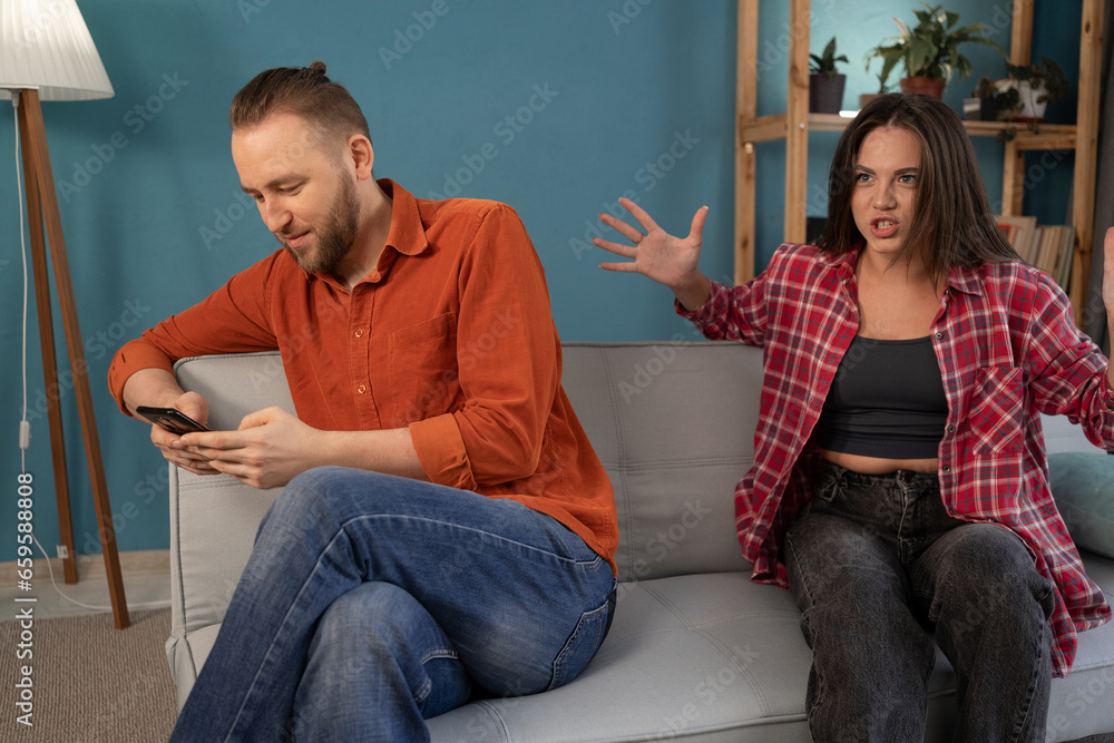 Annoyed angry young woman yelling at her man who using smartphone and ...