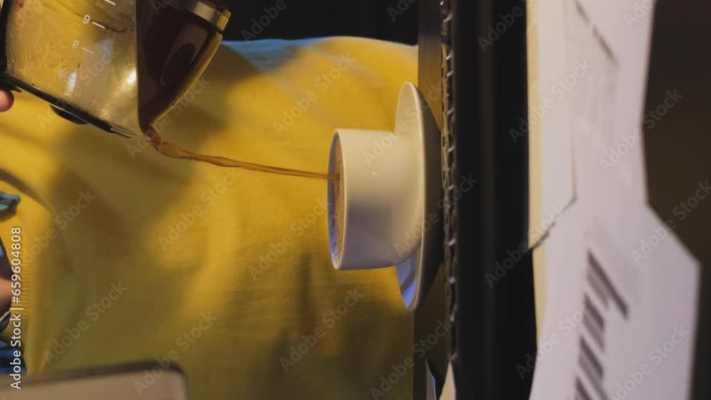 Vertical video. Close-up of tired man pouring coffee while working at ...