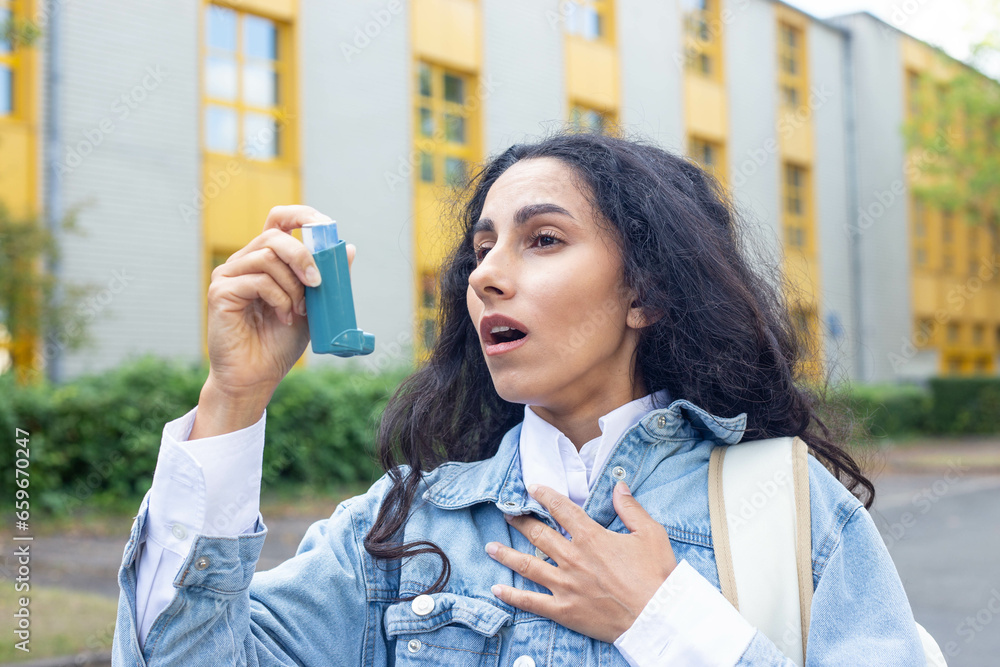 Young Eastern girl has an asthma attack or panic and holds an inhaler ...