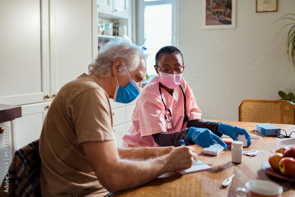 Young African American caregiver going over medication with her senior ...