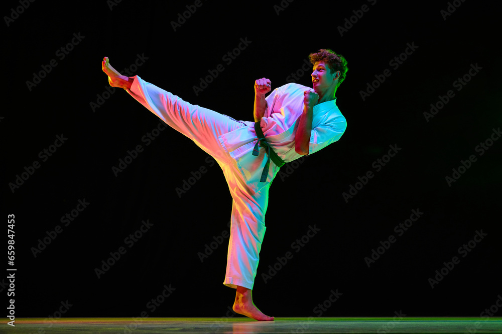 Leg kick. Professional combat sport athlete, karateka in white kimono ...