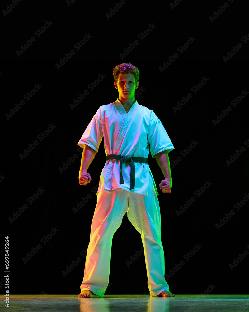 Full-length portrait of young sportive guy, karate athlete in white ...