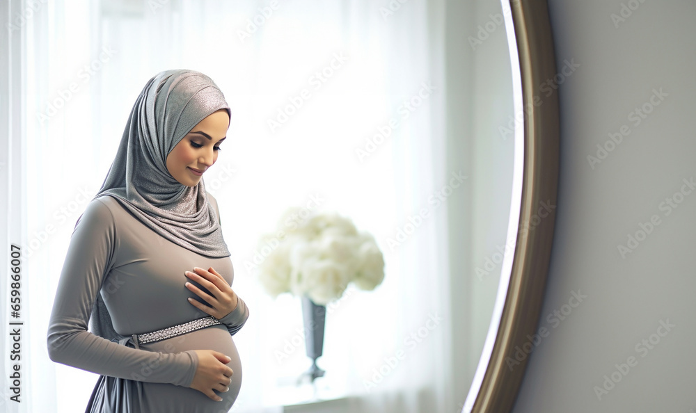 Pregnant muslim woman in hijab embracing her belly and posing over gray ...