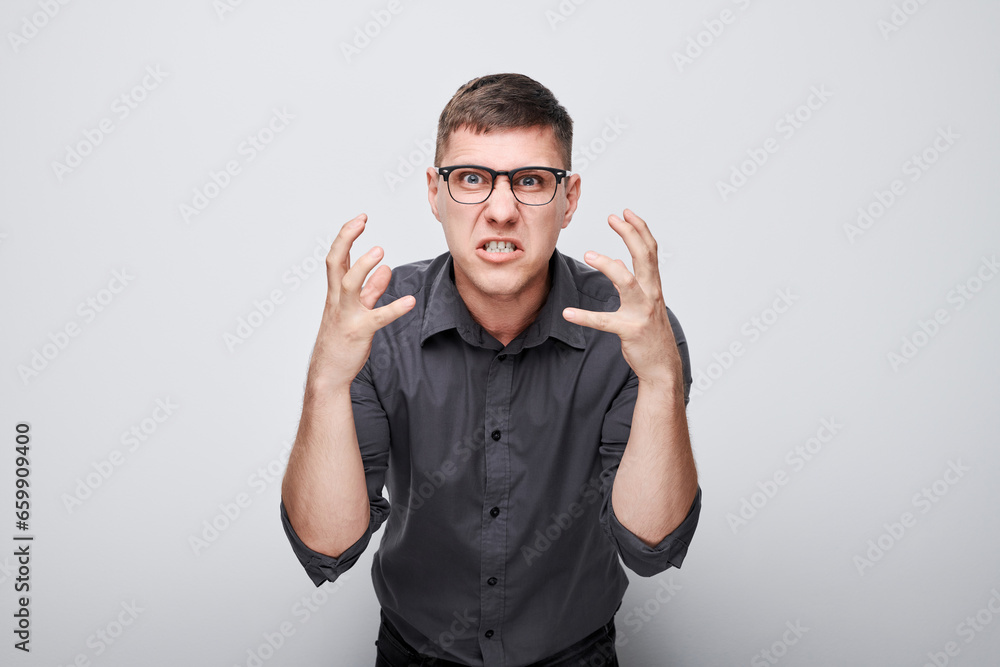 Portrait of angry young man screaming holding hands in furious gesture ...