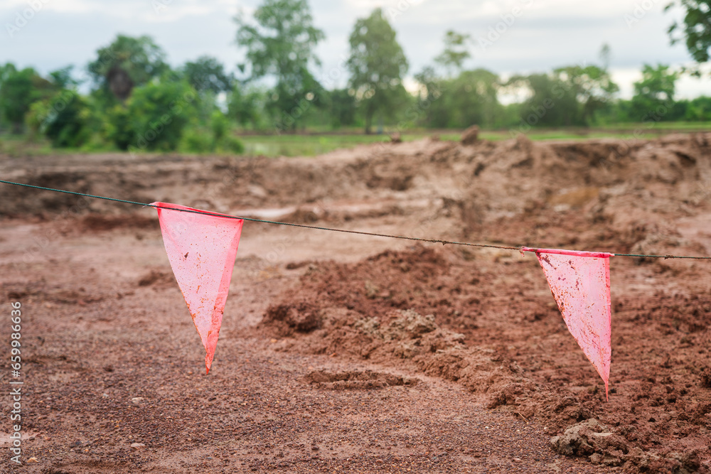 Red flag line to barricade the excavation working site with wet soil ...