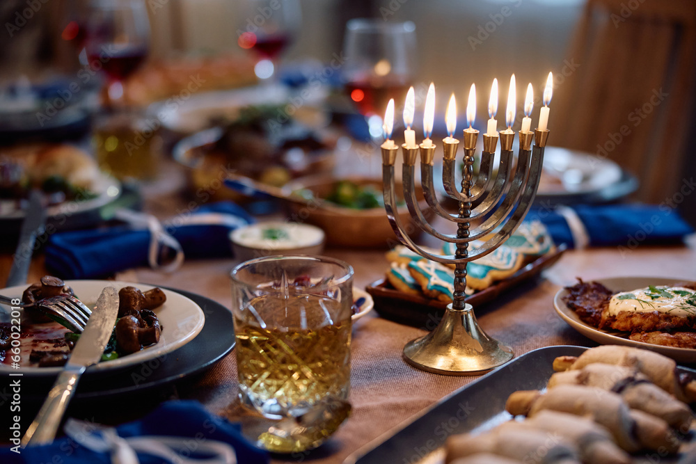 Lit candles in menorah on dining table during Hanukkah meal at home ...
