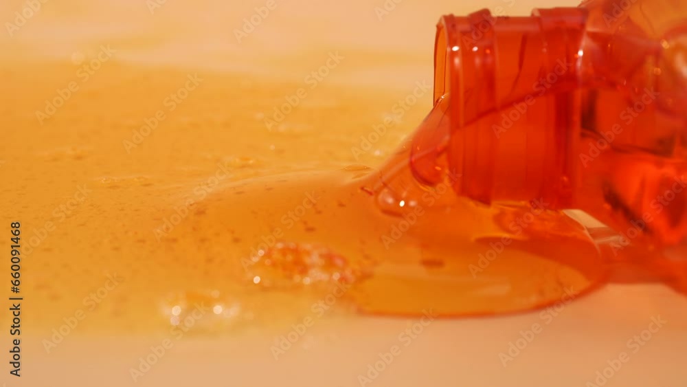 Liquid shower gel gracefully pours from a container onto a bright ...