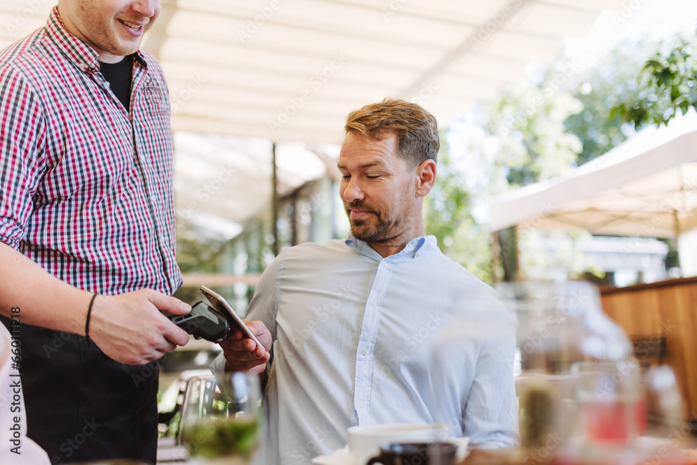 Man paying for lunch in restaurant, paying by card. Holding card near ...