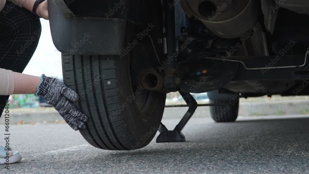 Woman wearing protective gloves rotates rear wheel and touches screw ...