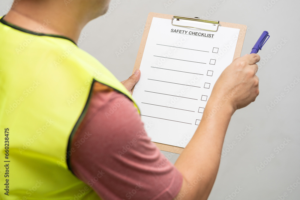 Action of safety officer is writing and check on checklist document ...