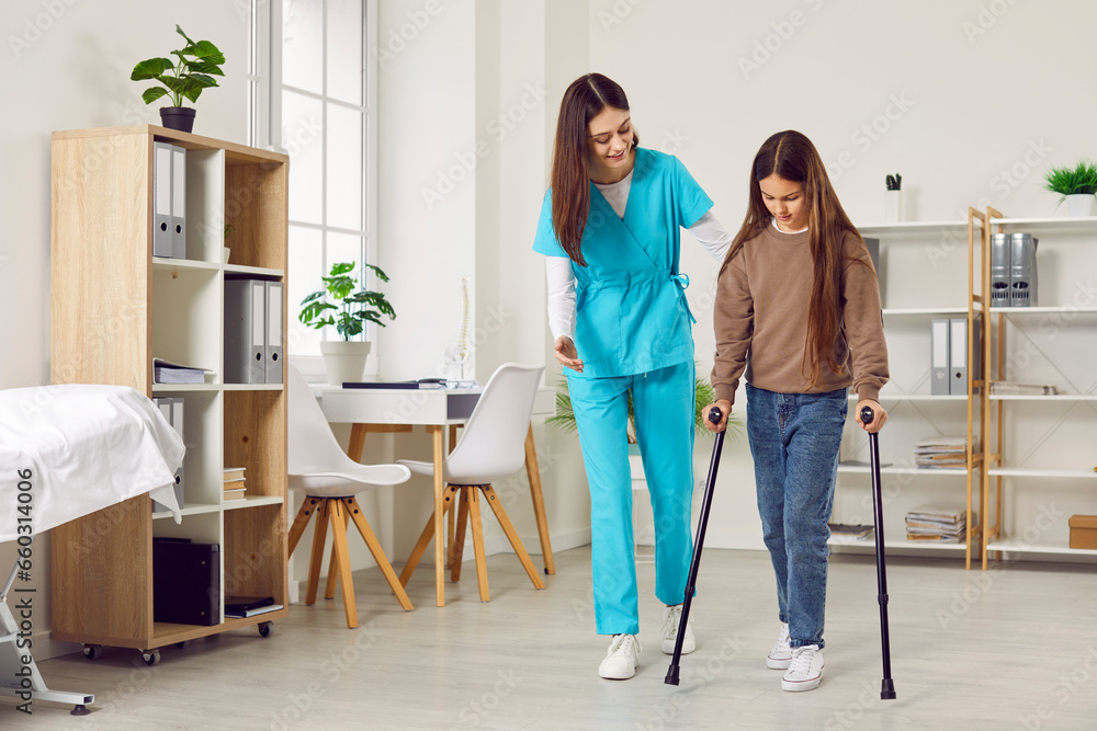 Woman doctor or nurse in a medical scrubs uniform helps a little kid ...