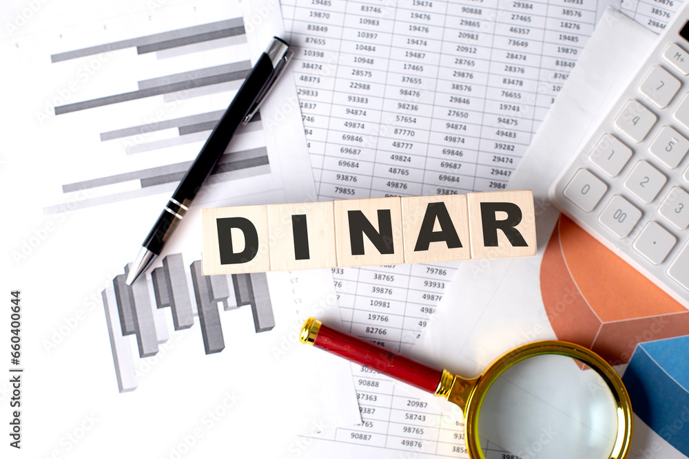 DINAR text on wooden block on graph background with pen and magnifier ...