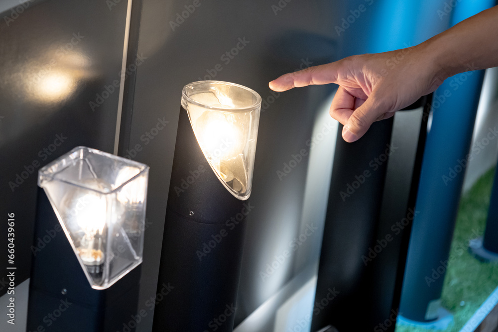 Designer hand pointing at sample of outdoor solar bollard garden lamp ...