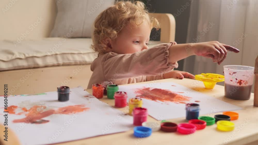 Cute diligent baby girl learning painting with water colors and fingers ...