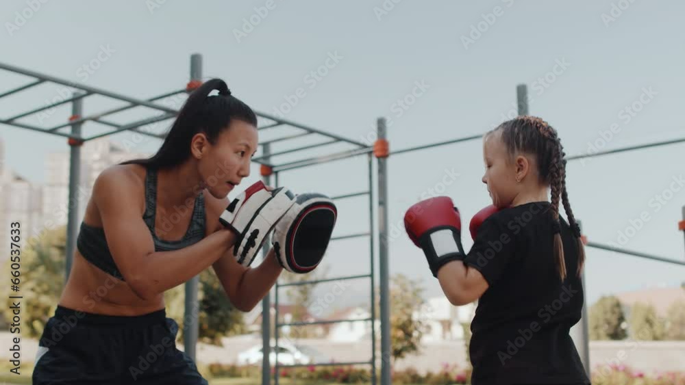 Vidéo Stock Young asian trainer in boxing paws practices double punch ...