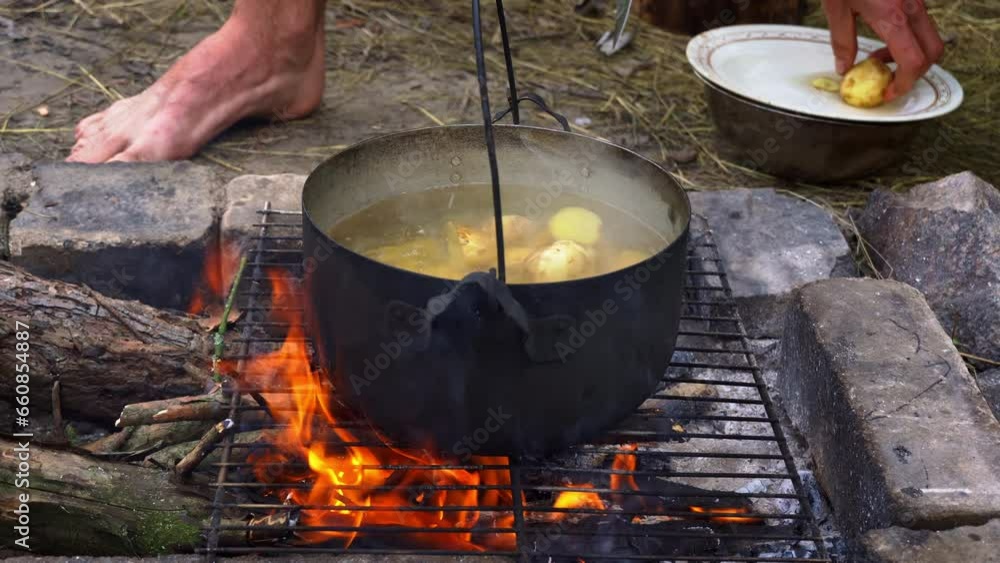 Potatoes are cooked in a large cauldron over an open fire during the ...