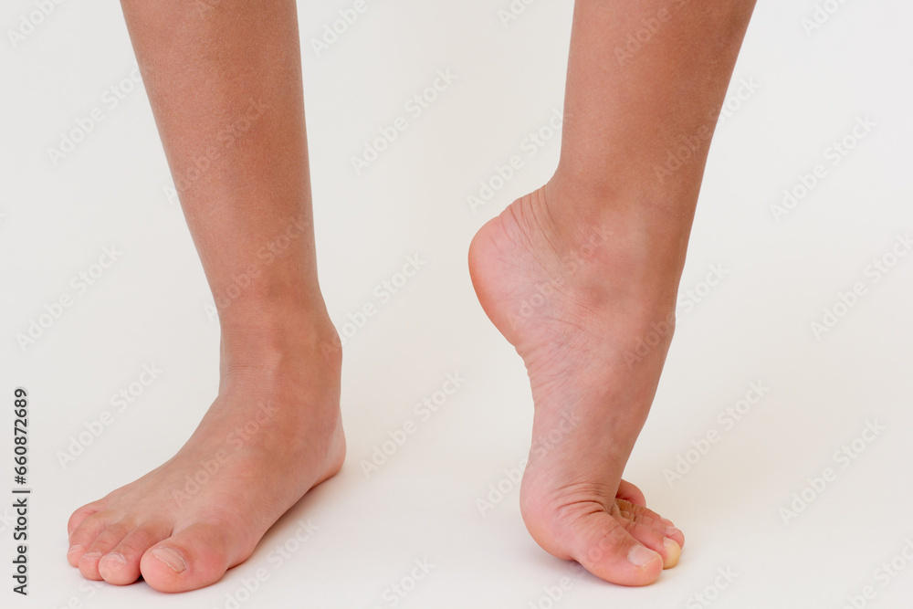 Cropped child legs with lifted heels on white background.Concept is ...