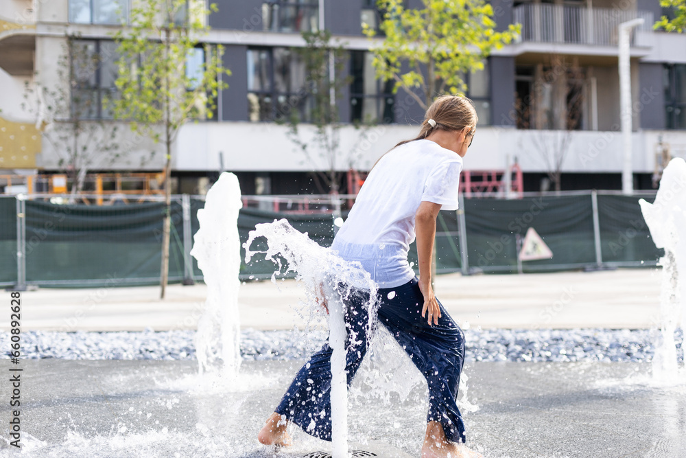 Cheerful young teen girl in city fountain, girl in wet clothes is ...