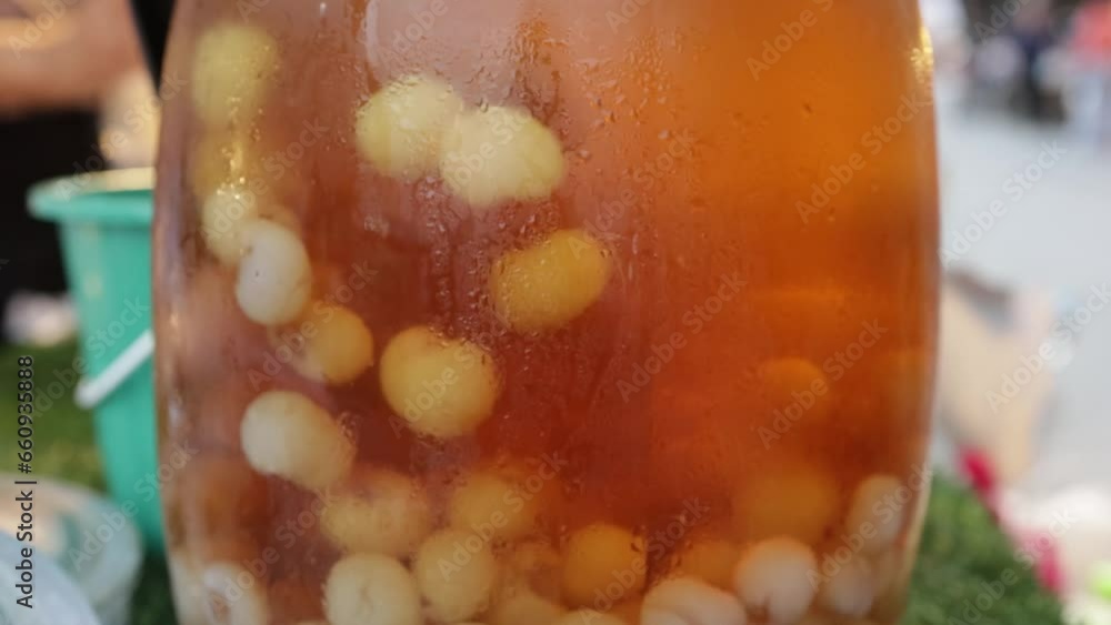SLO MO: Fresh longan flesh floating in longan juice in a big glass jar ...