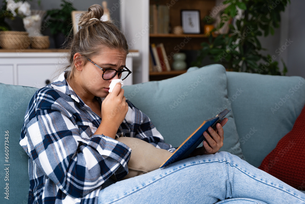 Sad woman crying while she reading a good paper book sitting on a sofa ...